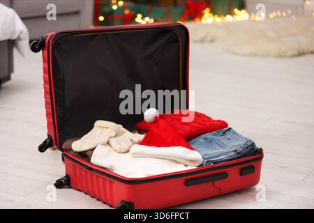 Christmas vacation. Suitcase with Santa hat, clothes and gift box on ...