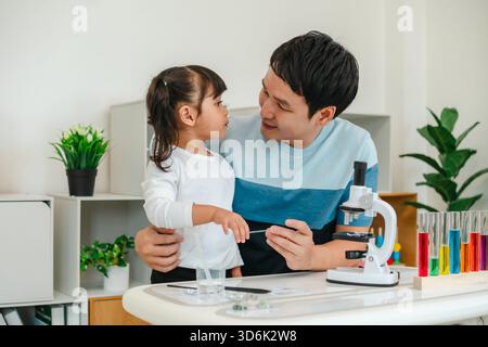 father and toddler girl scientist placing microscope slides with ...