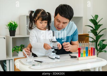 father and toddler girl scientist placing microscope slides with ...