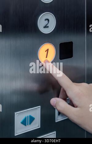 The hand of a girl kid presses an elevator button, showing a finger ...