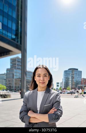 Young adult businesswoman smiling, standing confidently with arms ...