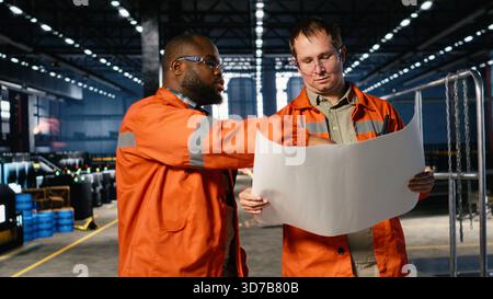 Diverse engineers handling assembly workflow with industrial plans ...