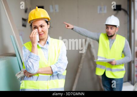 Crying female builder at construction site with displeased foreman ...