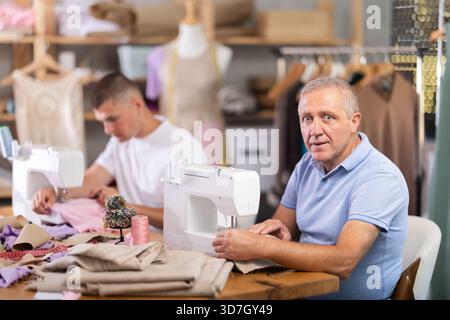 Two male workers in the atelier sewing Stock Photo - Alamy