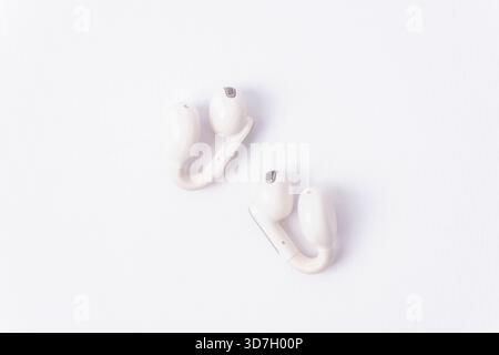 Pair of white wireless earbuds on plain surface. Clean, minimalist ...
