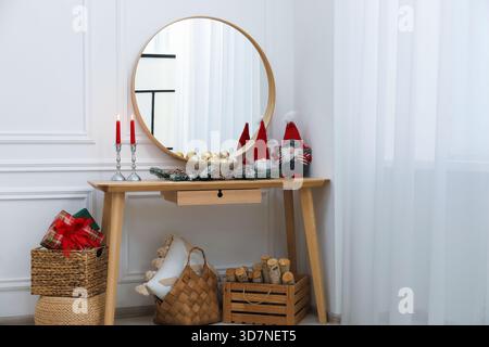 Mirror, Christmas decor on console table and firewood near white wall ...