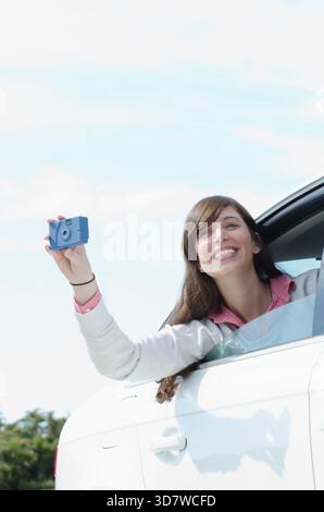 Young woman photographing through instant camera in front of shopping ...