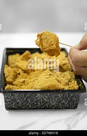 A tray of soft and jelly-like warabi mochi coated generously with ...