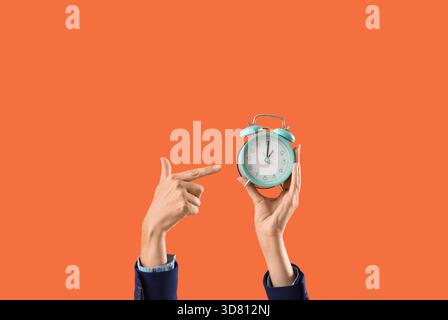 Female hands pointing at alarm clock on lilac background Stock Photo ...