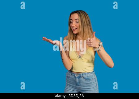 Woman smiling with palm up gesture toward parked coach buses in a depot ...