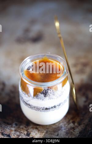 sweet homemade yogurt with fresh plum slices in a glass on a wooden ...