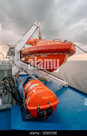 Orange lifeboat hanging from davit on a ferry boat at sunset Stock ...