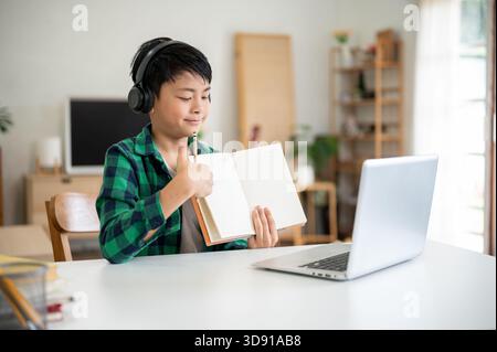 Excited asian schoolboy looking at laptop on beanbag chair on blue ...
