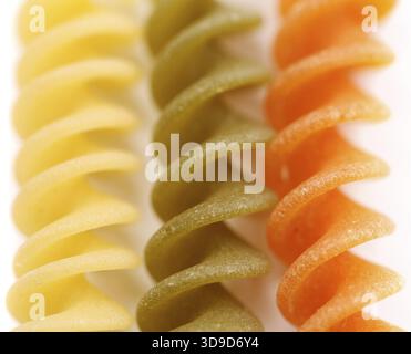 Close-up pasta eliche tricolori are located on the white background ...