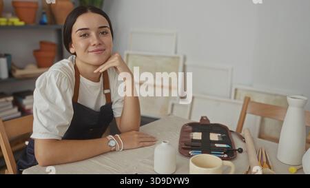 Young woman potter resting in cozy home pottery studio, drinking tea ...
