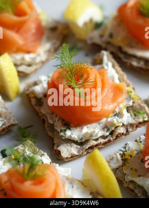 Closeup of crackers with cream cheese and salmon on them on the table ...