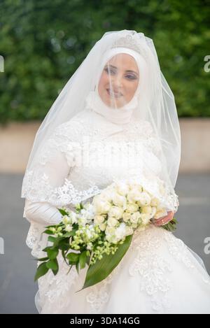 happy muslim bride with bouquet holding hands with blurred groom ...