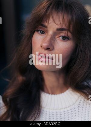 Serious female with makeup and freckles on nose gently touching skin ...