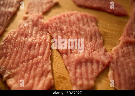 Thin raw meat slices arranged on rustic wooden cutting board. Fresh ...
