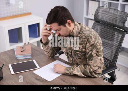 Military education. Student in soldier uniform learning at wooden desk ...