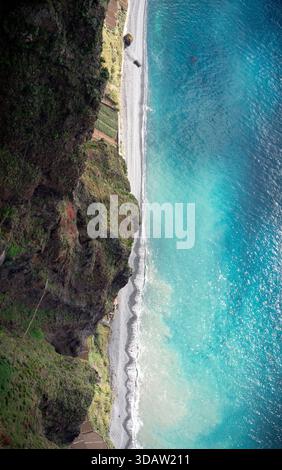 A dramatic coastal landscape showing steep green cliffs topped with ...
