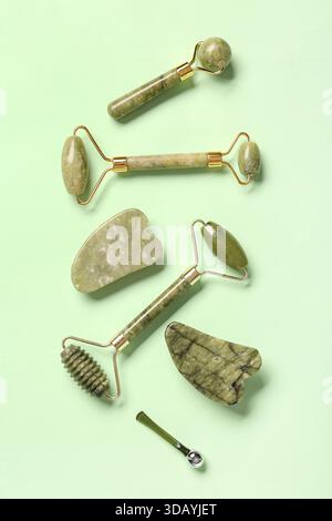 Different facial massage tools on green background Stock Photo - Alamy