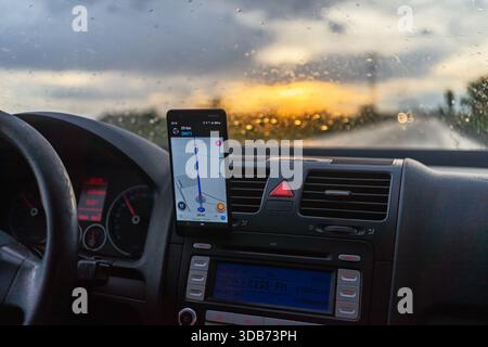 Driver using waze app on mobile phone mounted on car dashboard Stock ...