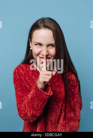 Smiling beautiful woman shushing, making hush shh sign, press finger to ...
