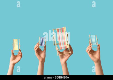 Female hands holding mini deck chairs with surfboard and diving goggles ...