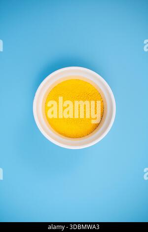 Bright yellow creamy cheese sauce in elegant white triangular bowl on ...