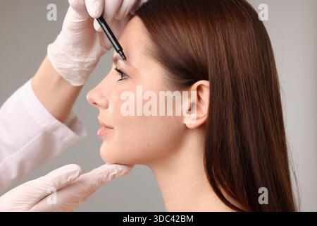 Doctor drawing marks on patient's face for plastic surgery operation ...