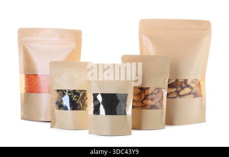 Stand-up pouches with different products on wooden table against white ...
