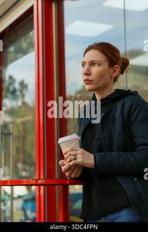 A woman holds a red cup while standing by a Christmas tree Stock Photo ...