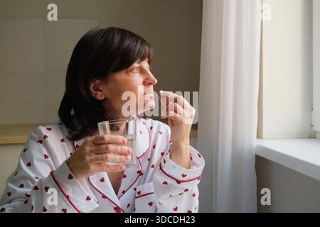 Menopause. Woman with glass of water suffering from heat flash at ...