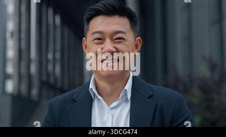 Thoughtful happy Japanese man smiling while talking on mobile phone ...