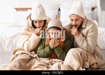 Frozen family with winter clothes and lack of heating hugging in ...