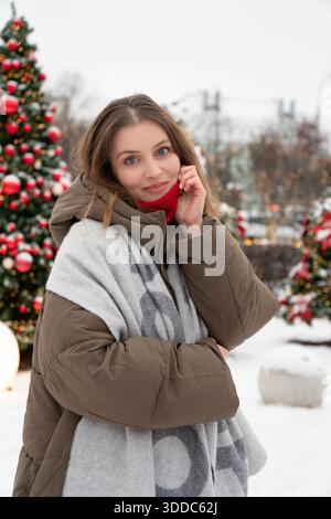 A woman stands near a Christmas tree with festive ornaments Stock Photo ...