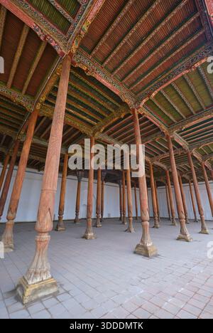 A view of an old mosque with a porch, portico of slender wood columns ...