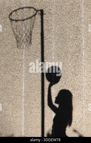 Shadow of girl shooting netball ball into netball goal net Stock Photo ...