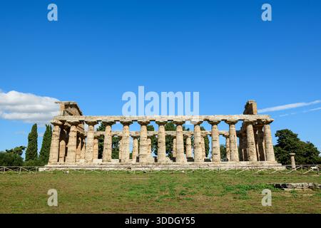 Ancient Doric temple at Paestum framed by trees, with mountains in the ...