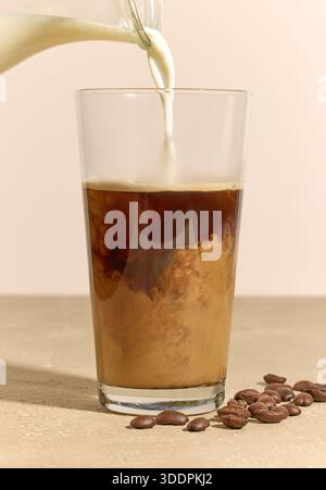 Pouring milk into glass cup and beans at wooden table, closeup Stock ...