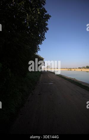 Dirt trail by the bank of a diversionary channel full of poppies ...