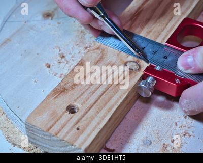 Carpenter marking pine wood plank for cutting in woodwork workshop ...