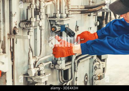 A close-up of a worker's hands adjusting a blue plastic fitting inside ...