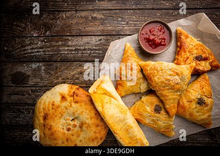 Samsa or samosas with meat or vegetables and pita with tomato sauce on ...