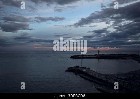 Sea stretching to the horizon with breakwaters on a cloudy nightfall ...