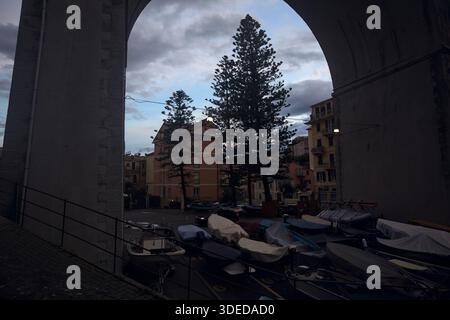 Square under the arches of a bridge with trees and covered boats in an ...