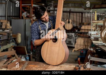 Wood artisan sanding guitar body, creating musical instrument in ...