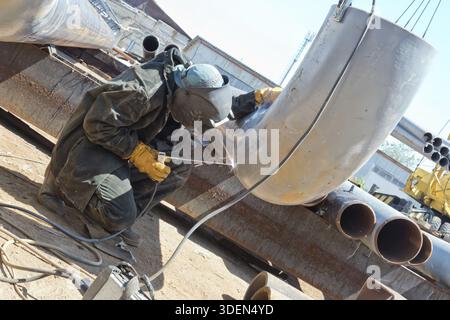 Welder is repairing the defective area of the weld inside the parts of ...