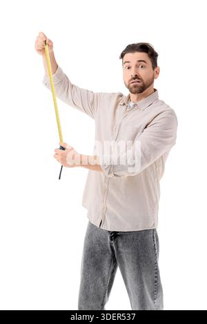 Shocked young man with tape measure around his waist and scales on blue ...